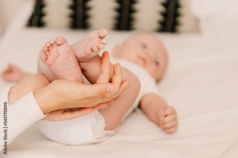 Little funny cute boy, mother hold child legs, baby lying on bed, ready ...