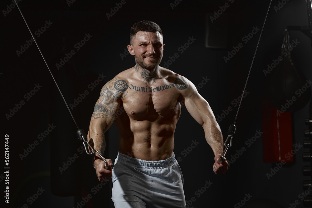 Muscular man training shirtless in gym indoors. Doing lat pulldown ...