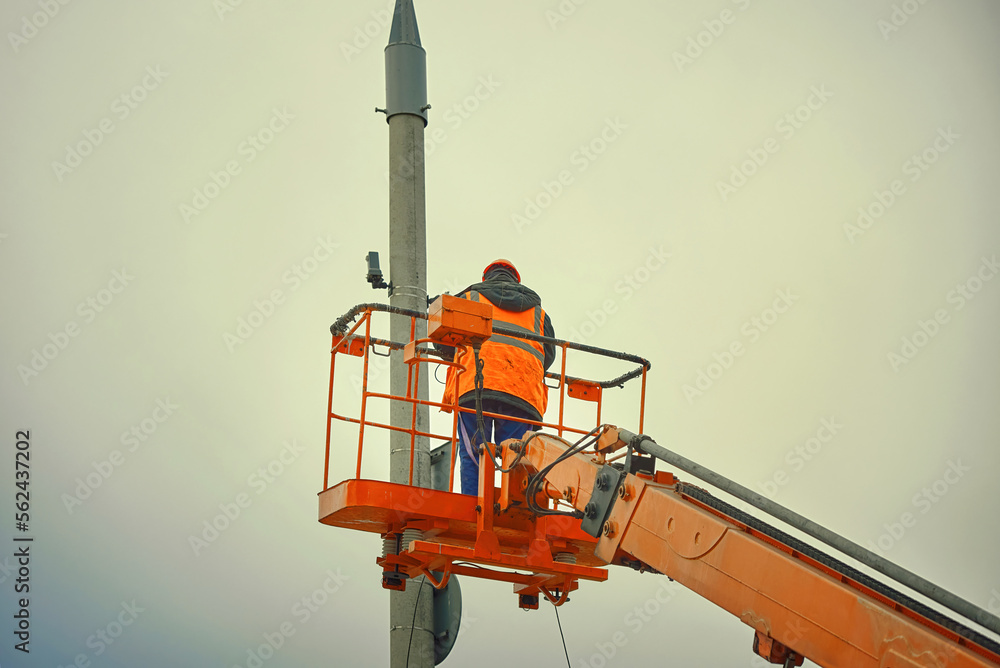 Foto Worker in lift bucket repair street light. Worker repairing street ...