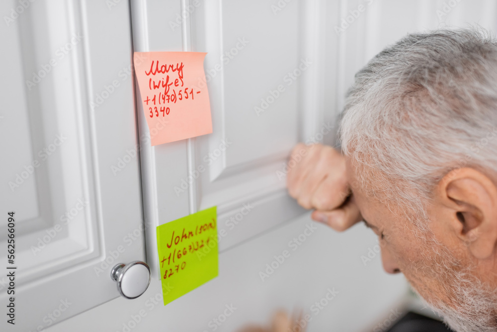 stressed man suffering from memory loss and standing near sticky notes ...
