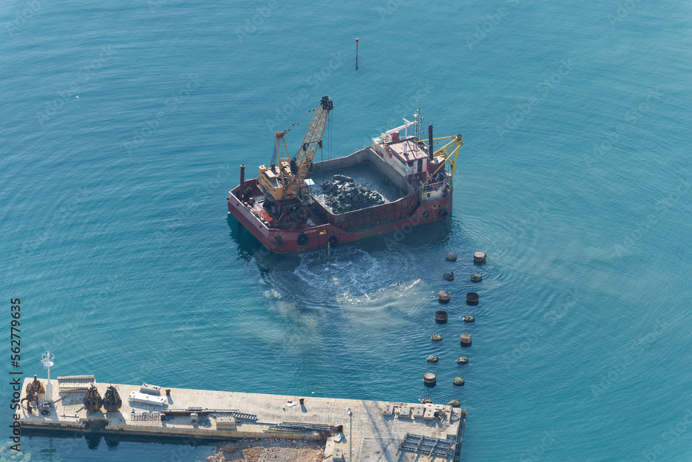 A boat is dredging the sea. Dredging is the removal of sediments and ...