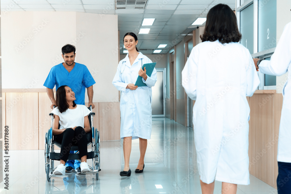 Doctor and male nurse transport a female patient in a wheelchair along ...