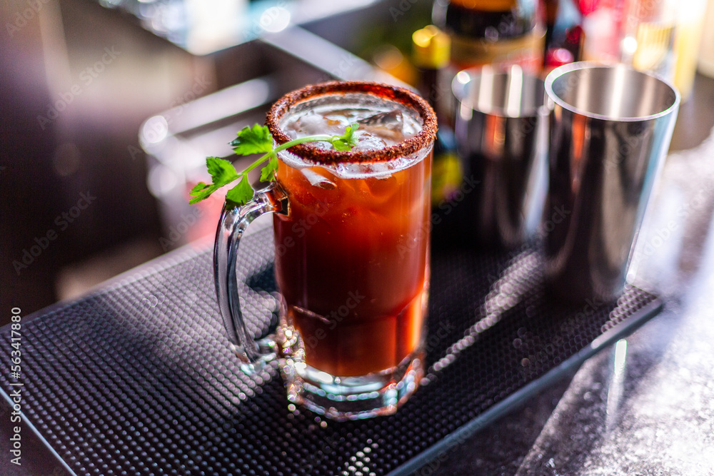 Preparación de michelada, cerveza en tarro en restaurante preparada con pepino, camarón, chile ...
