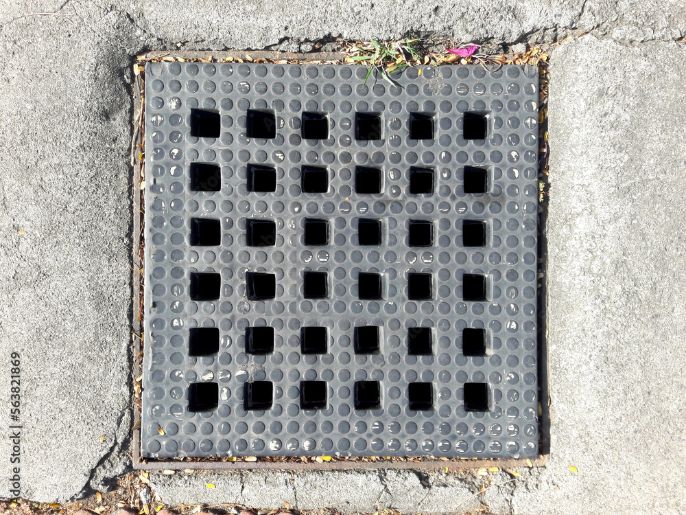 Blacktop drains are covered with square plastic grids. Road covered ...