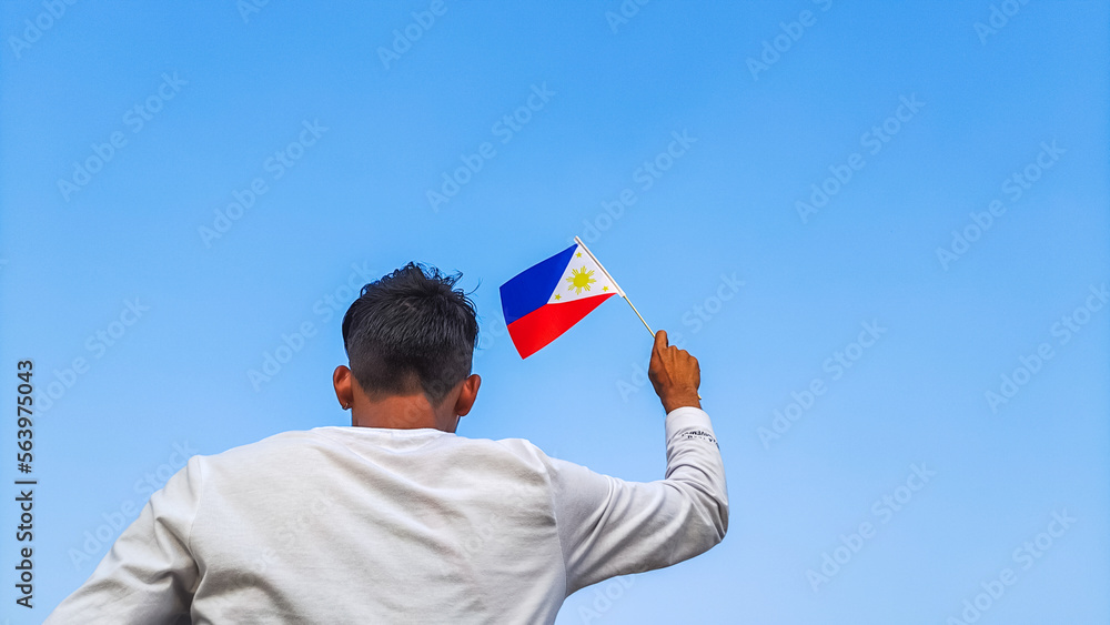 Boy holding Philippines flag against clear blue sky. Man hand waving ...