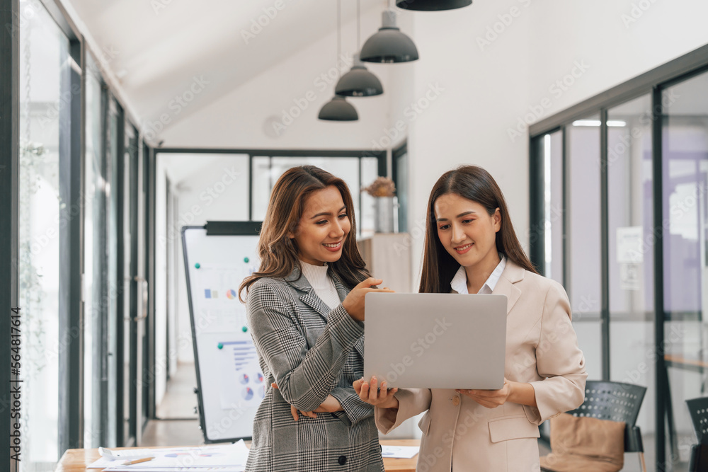 Two young pretty asia business woman in suit talking together in modern ...
