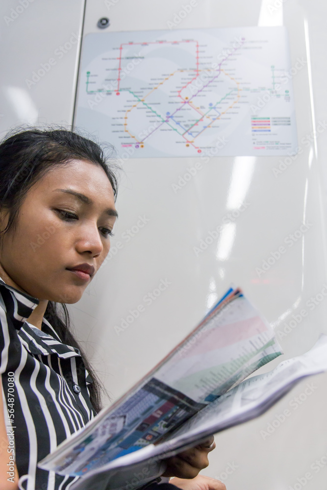 Asian tourist looks at the maps in the subway. A woman reading urban ...