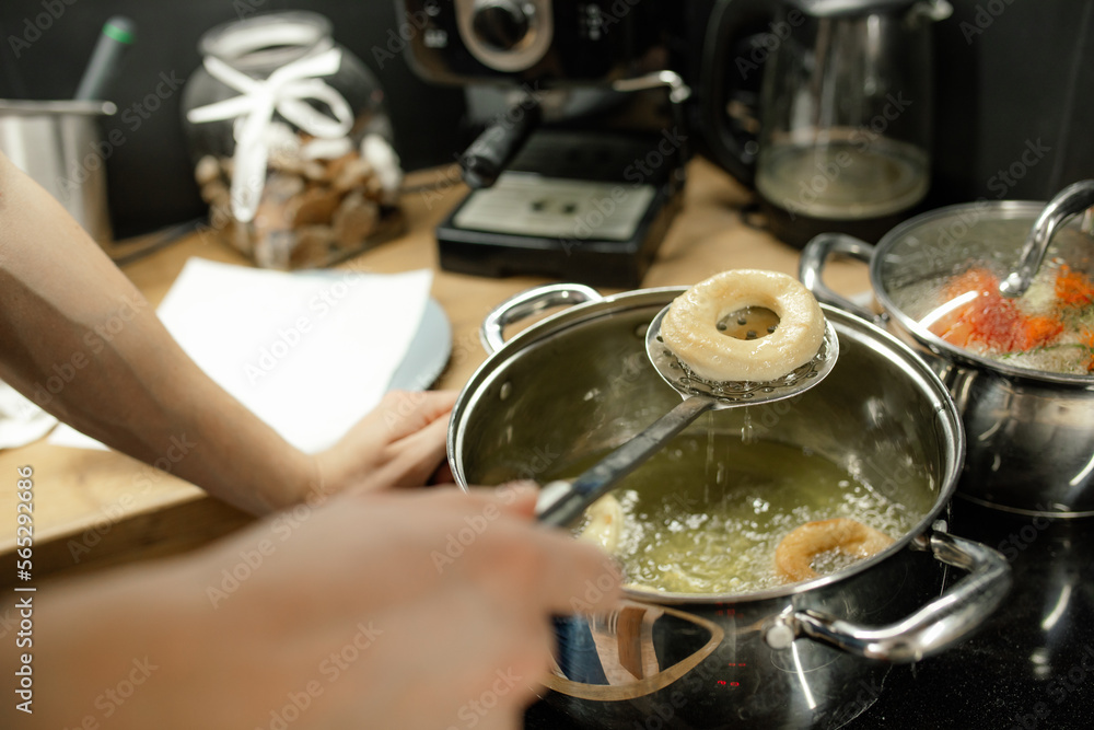 Deep fry dough donuts closeup. Take out ready bagels with slotted spoon ...