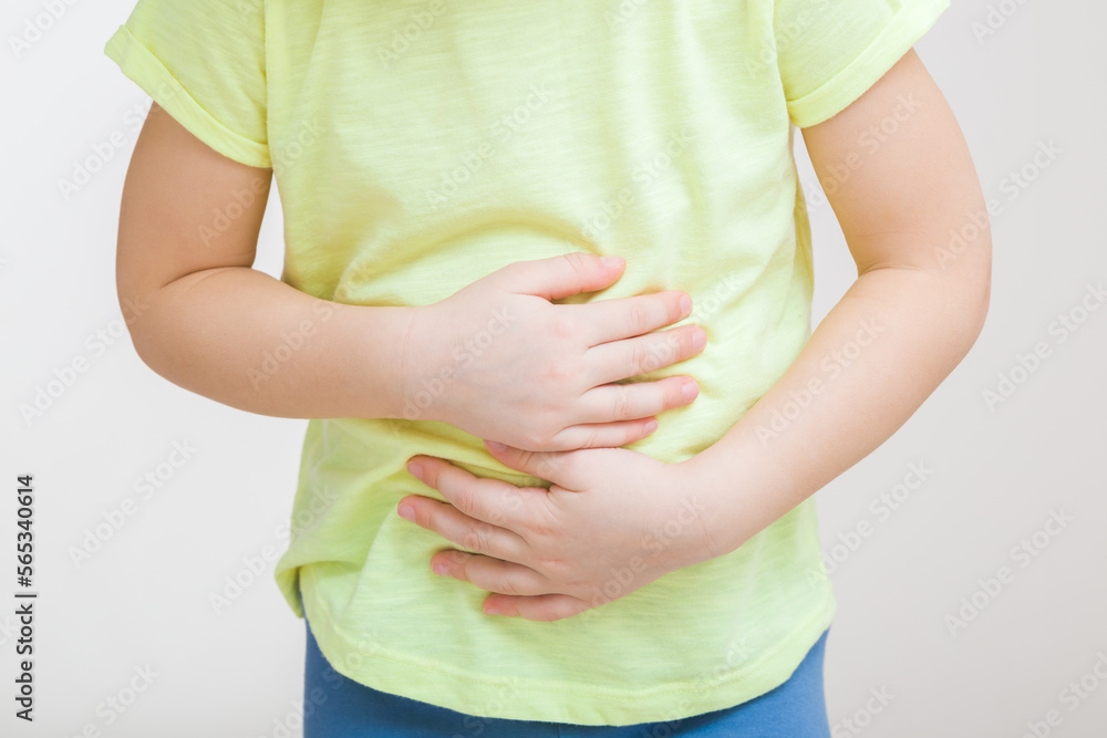 Little girl touching painful belly with arms isolated on light gray ...