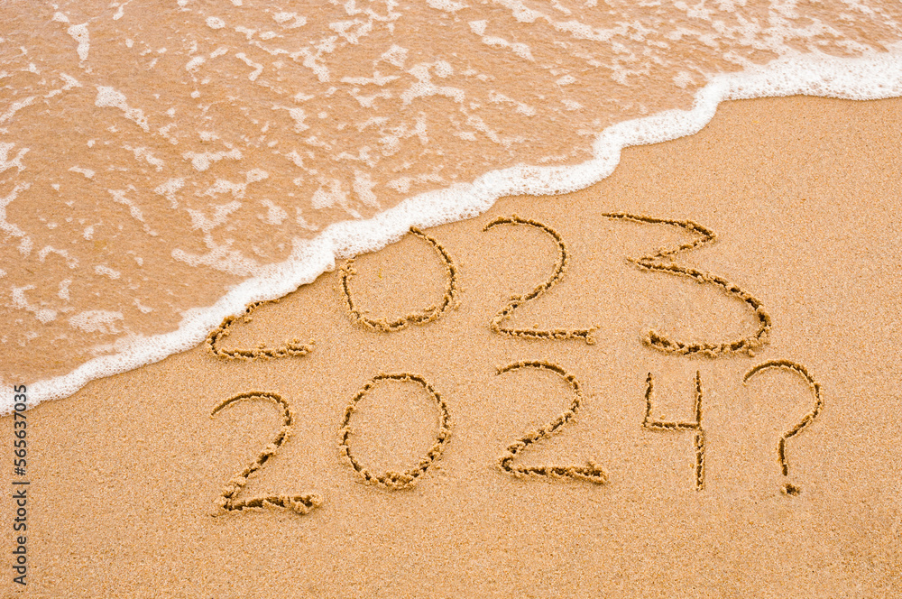 Inscription 2023 and 2024 numbers written on sand with question mark ...