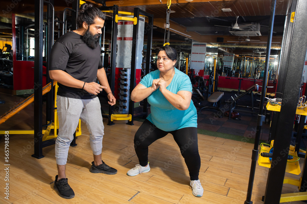 Young overweight indian woman workout in gym with trainer to lose ...