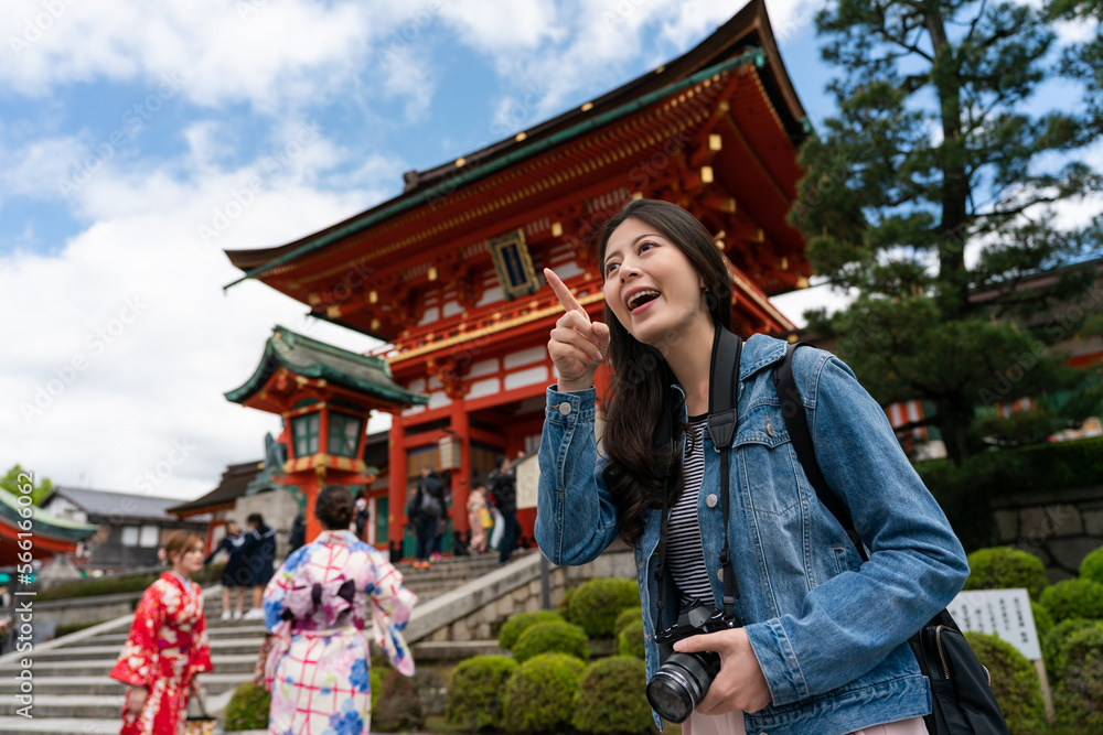 cheerful asian female visitor pointing at landmark in distance at the ...