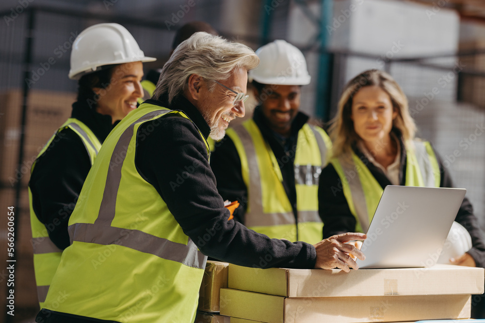 Successful warehouse team watching a presentation on a laptop Stock ...