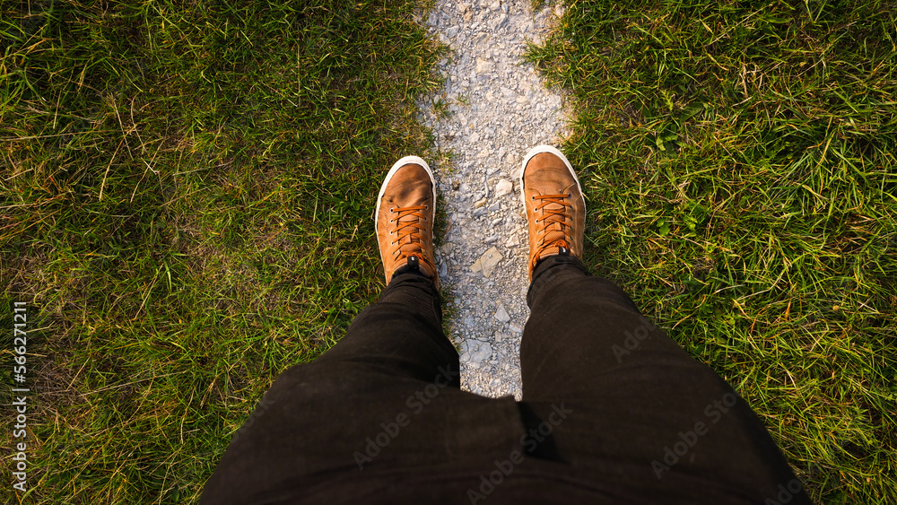 Top down to male feet on narrow path in grass, dressed in brown lace ...