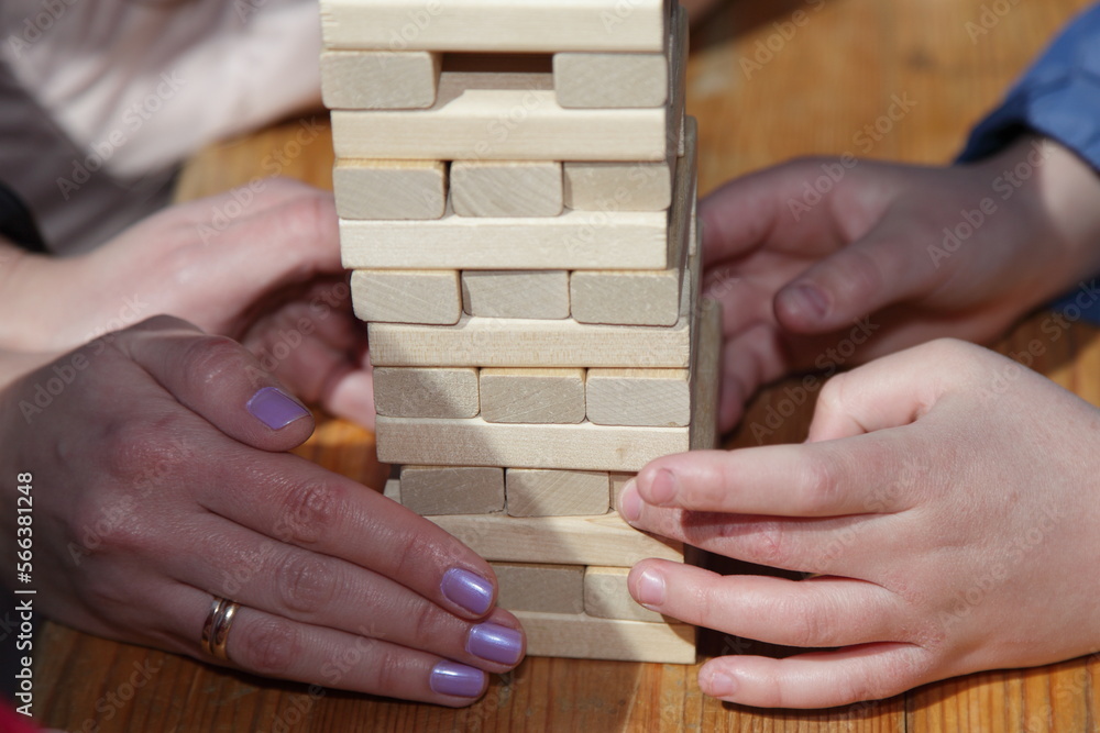 Women's and children's hands hold together a pyramid of wooden cubes of ...