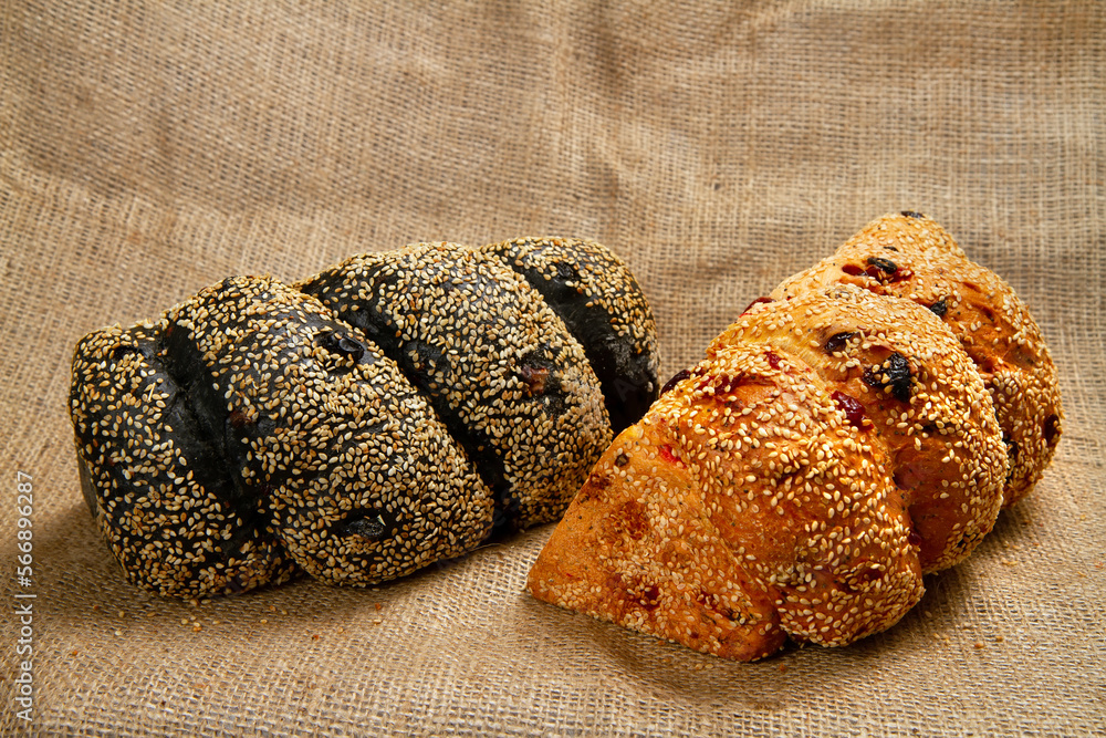 Triangular loaves of bread with sesame against the background of burlap ...