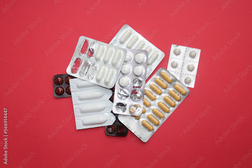 Random tablets and capsules pill in blister packaging on the red ...