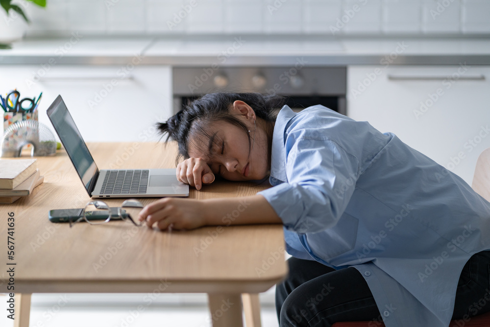 Tired exhausted Asian woman sleeping in kitchen with head on desk near ...