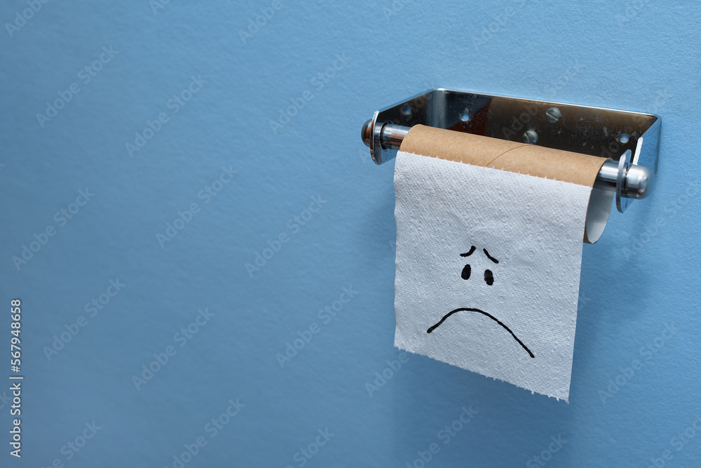 Sad face on the last piece of toilet paper tissue on a brown cardboard ...