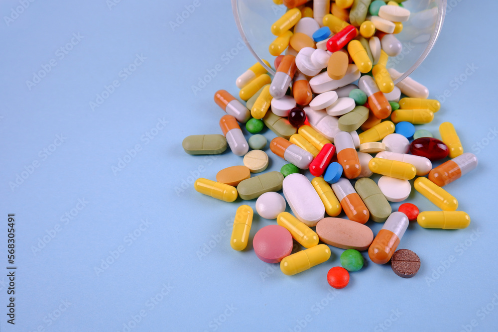 There are a lot of pills, capsules that pour out of a glass on a blue ...