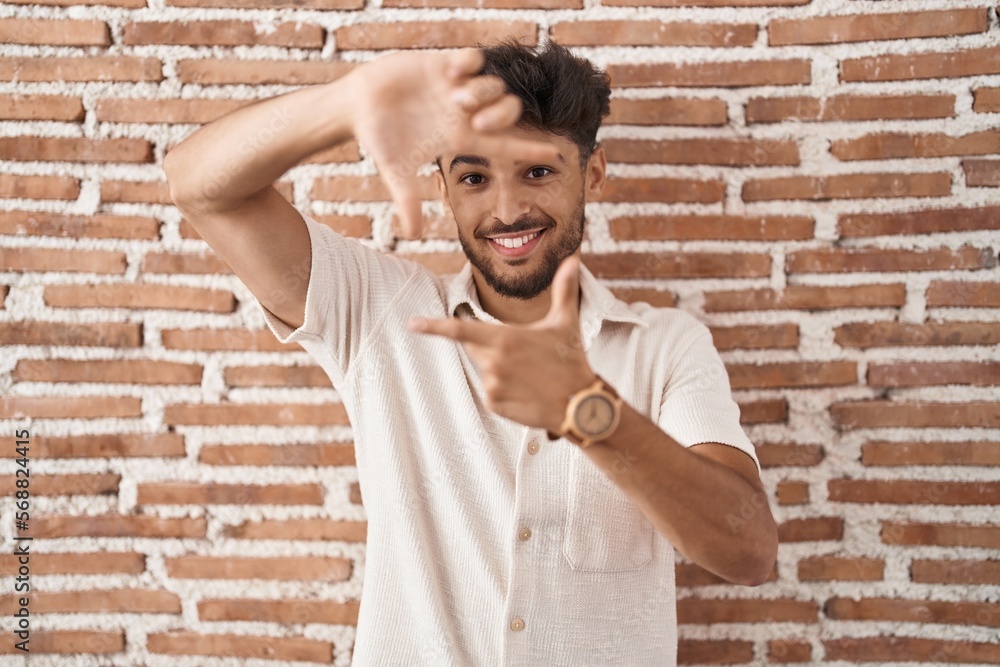 Arab man with beard standing over bricks wall background smiling making ...