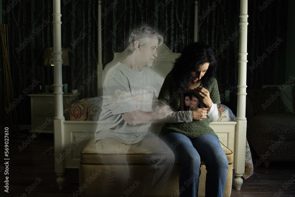 A sad woman clutching a photo of herself and her dead husband is being ...