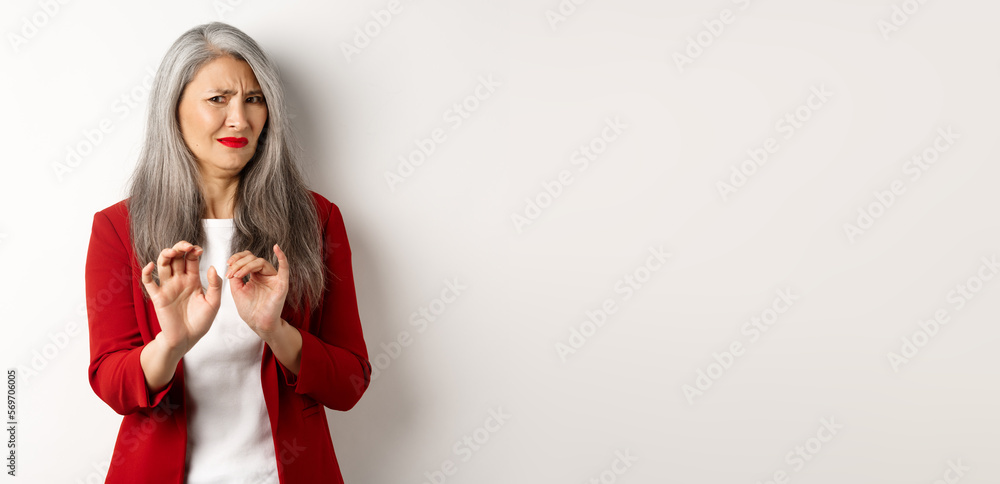 Disgusted asian businesswoman with grey hair, wearing red blazer and ...