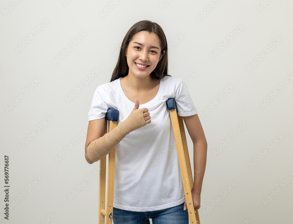 Stock-Foto „Happy young asian woman broken arm and leg on isolated. Woman put on plaster cast ...