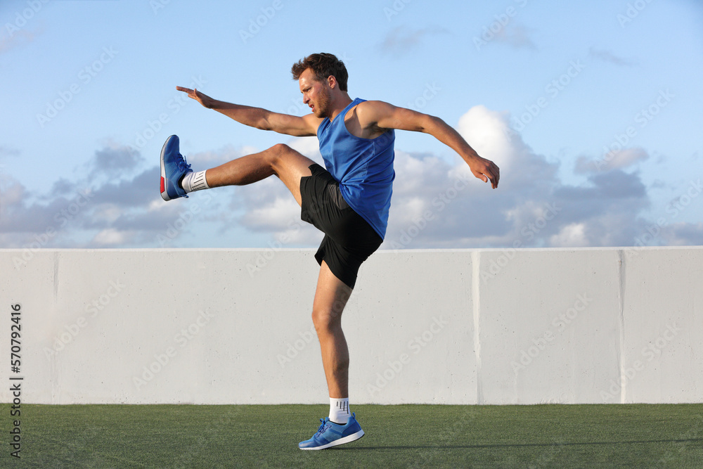 Runner man getting ready to run doing warm-up dynamic leg stretch ...