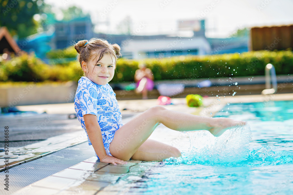 Little preschool girl playing in outdoor swimming pool by sunset. Child ...