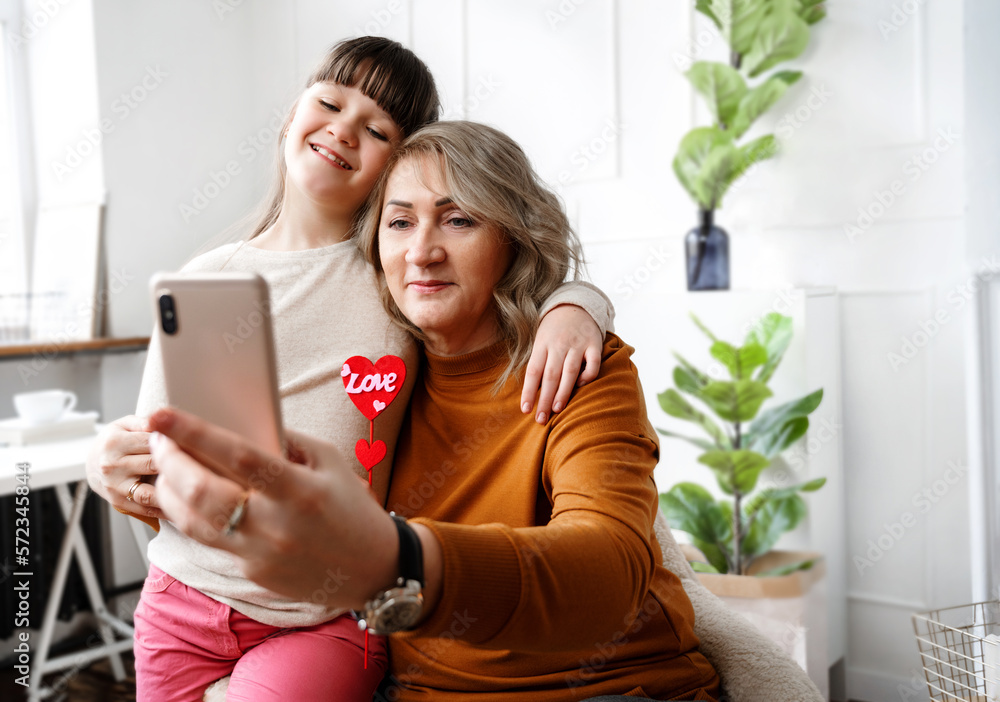 Mature mother with daughter hug and does selfie on mobile phone on ...