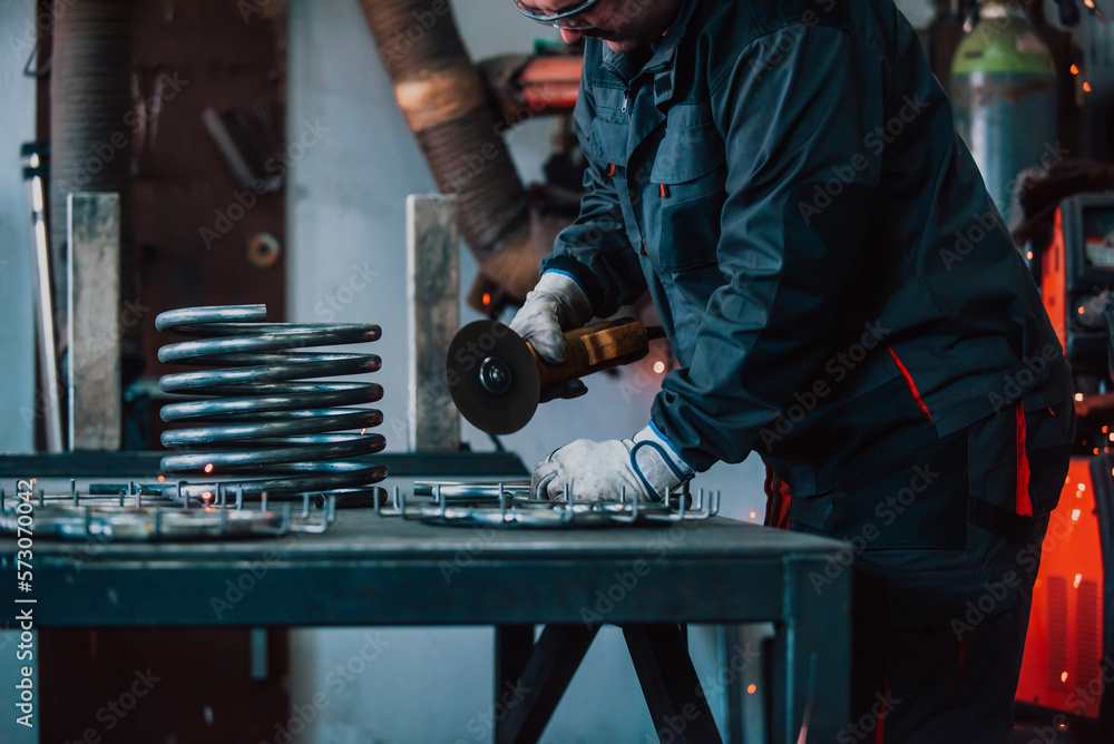 Locksmith in special clothes and goggles works in production. Metal ...