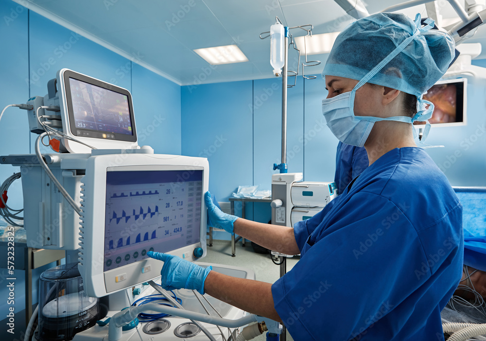 Nurse in operating room of hospital checking patient's vital signs ...