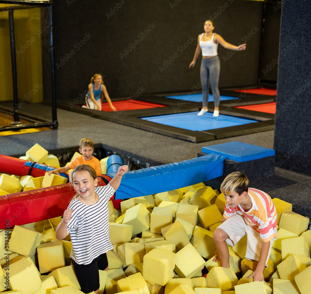 Happy laughing preteen girl and boy floundering in pit with soft foam ...