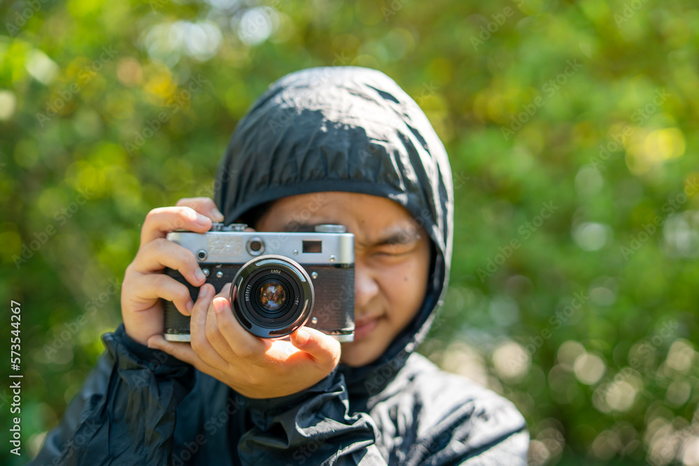 film camera in the hands of a girl taking a picture. Green trees ...