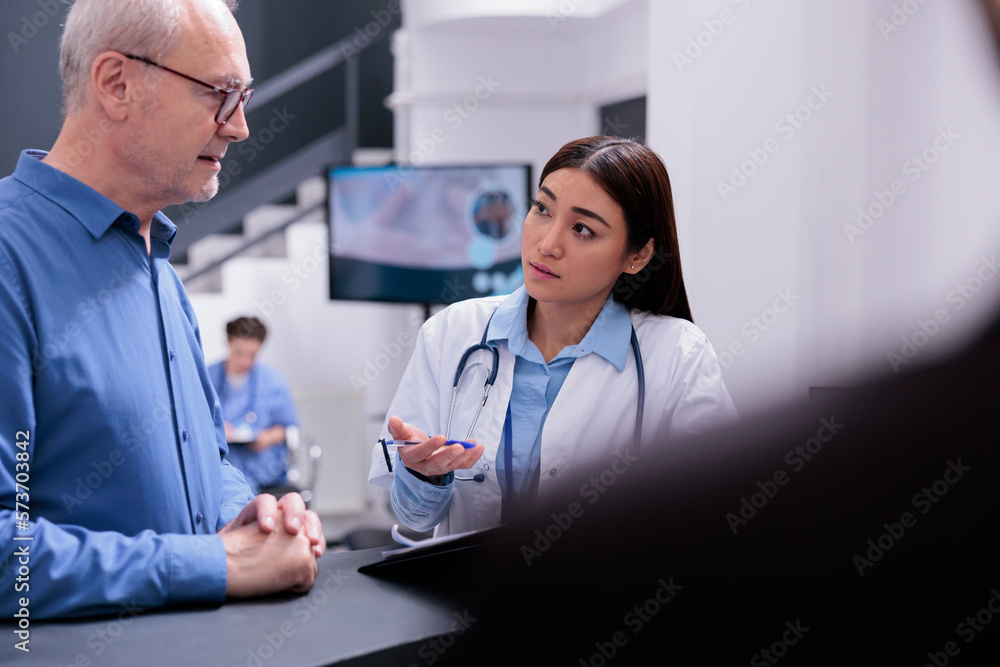 Medic standing at reception desk discussing medical expertise with ...