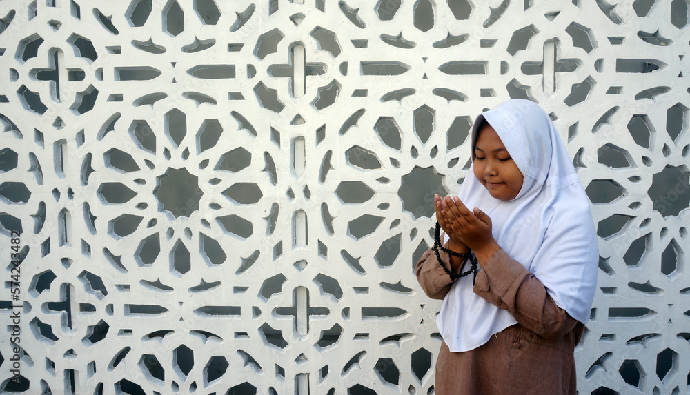 Muslim kid girl wearing hijab praying during Ramadan period. The ...