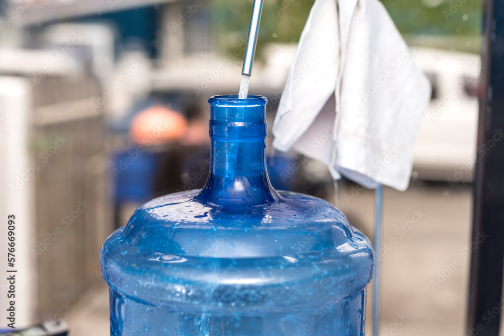 A cylindrical 20 liter HPDE water container being refilled with ...