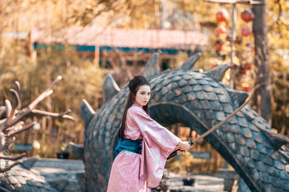 Japanese geisha in a traditional kimano with a fan and armed with a ...