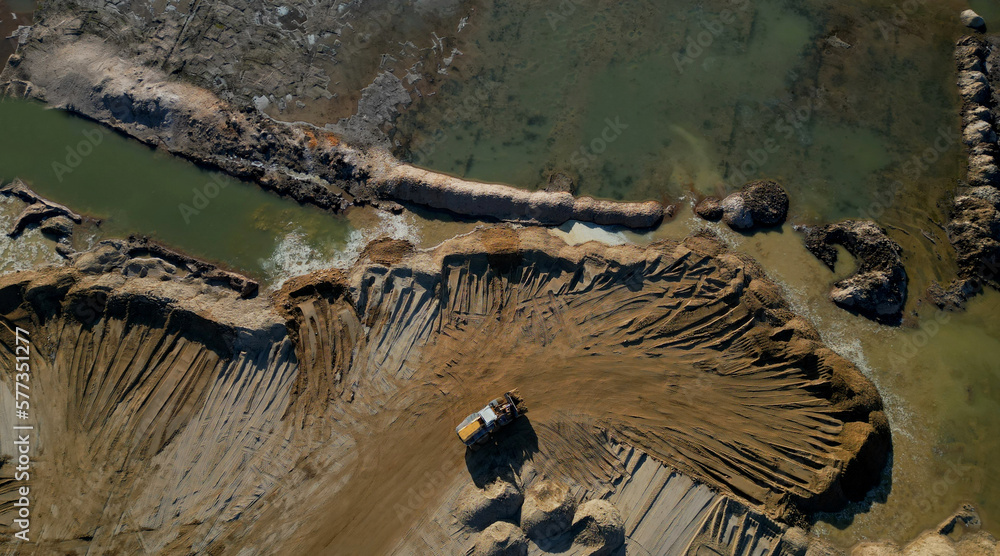Arial view of open pit sand mine. A front loader loads sand from piles ...