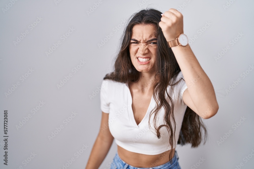 Young teenager girl standing over white background angry and mad ...