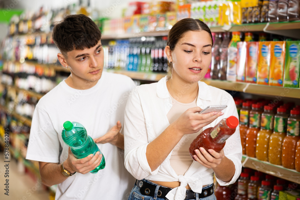 Positive young couple scanning barcodes on bottles with soft drinks ...