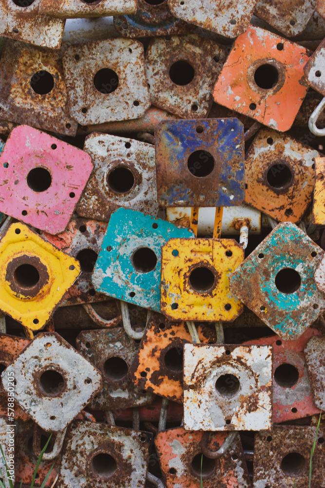 Old scaffold tubes are stored outside in a pile. Different colors ...