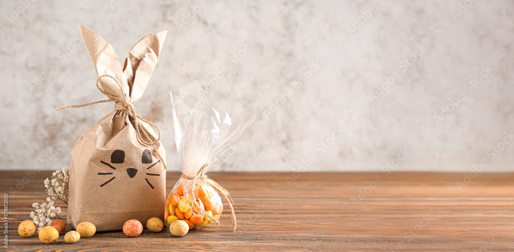 Easter bunny gift bag and candies on wooden table against light ...