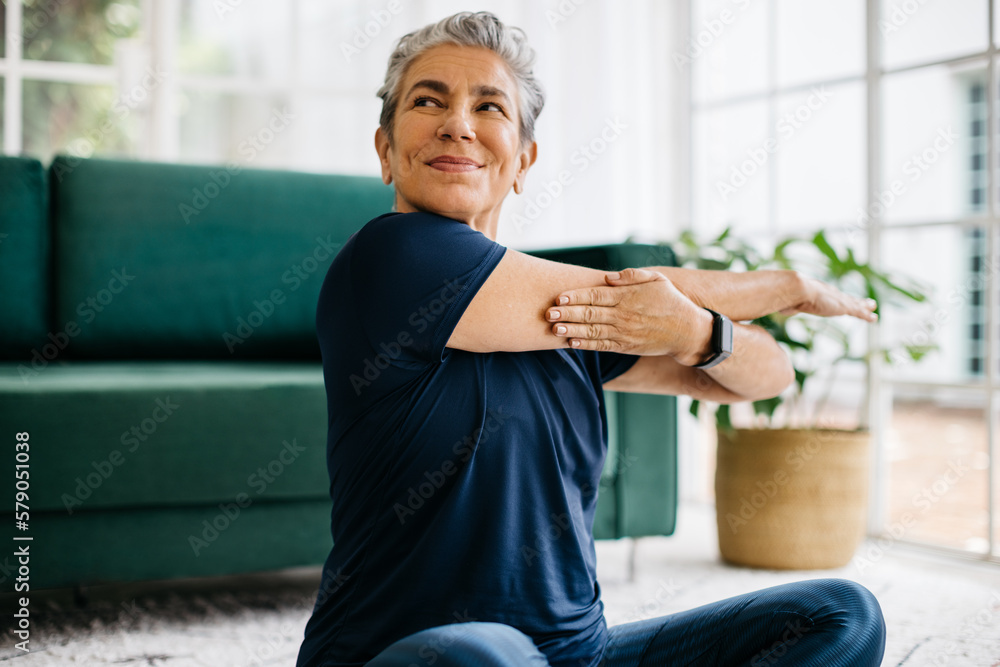 Happy and healthy senior woman doing a cross arm stretch in a peaceful ...