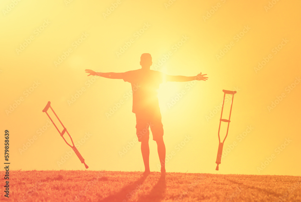 Silhouette a disabled man standing up and raising his crutches. Miracle ...