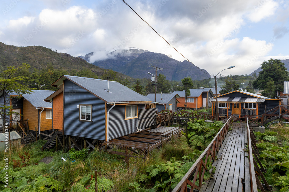 Small colorful houses and nalca plants along the wooden paths of Tortel ...