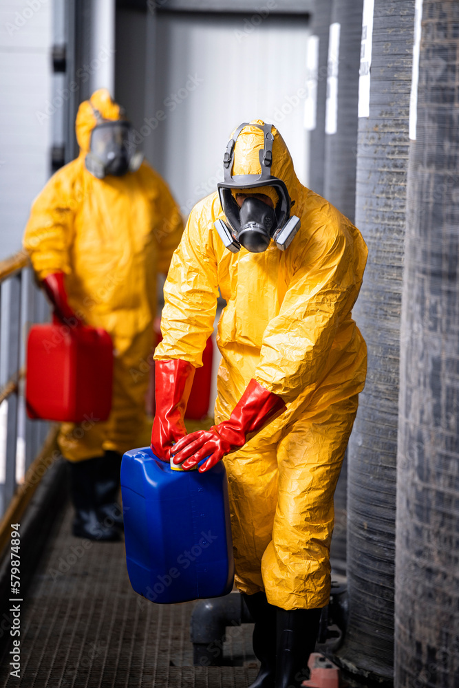 Fully protected workers in yellow hazmat suit, gas masks and gloves ...