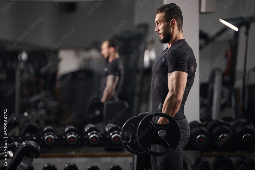 Side view of man lifting barbell while exercising at gym Stock Photo ...