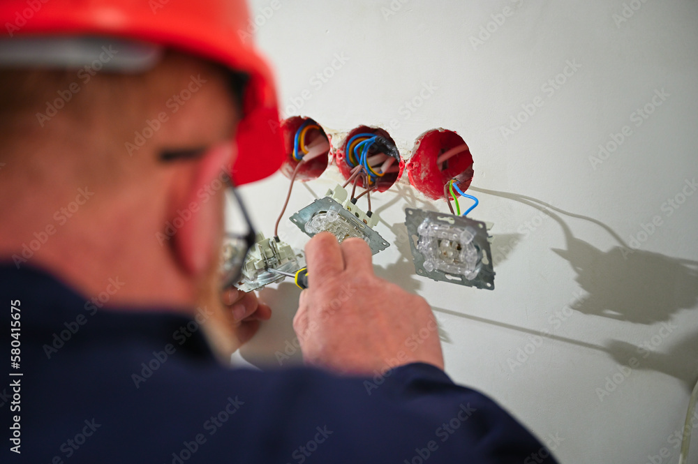 Professional electrician technician installing a wall socket in a new ...